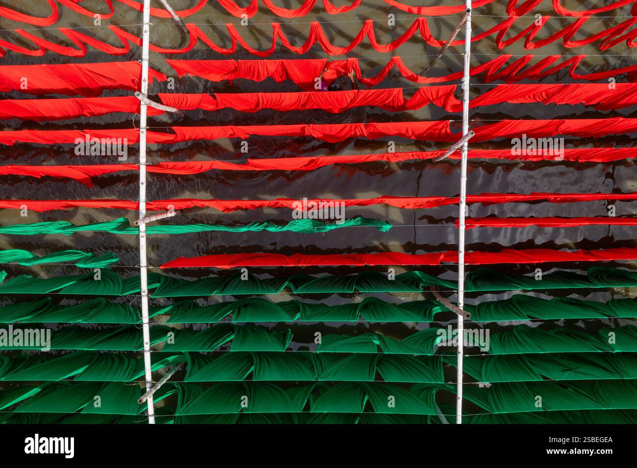 An aerial view captures freshly dyed fabrics drying under the open sky ...