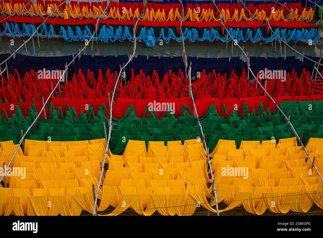 An aerial view captures freshly dyed fabrics drying under the open sky ...