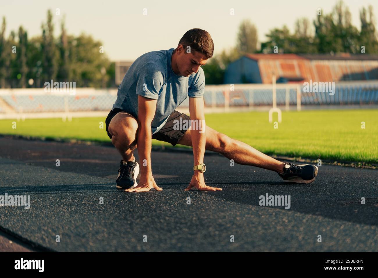 Young athlete stretches on the track during evening training session at ...