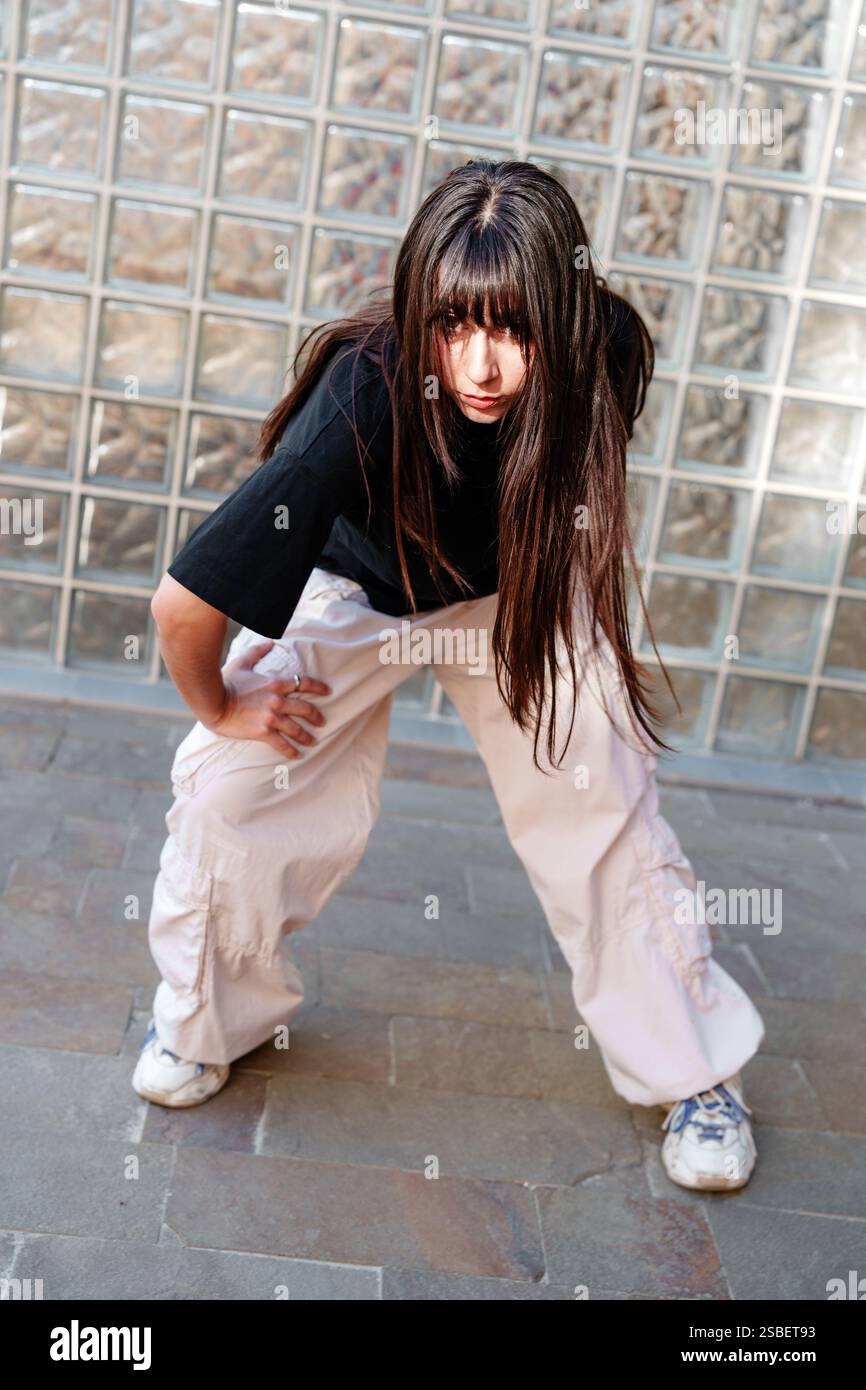 Dancer in urban environment showcases dynamic pose against glass wall ...