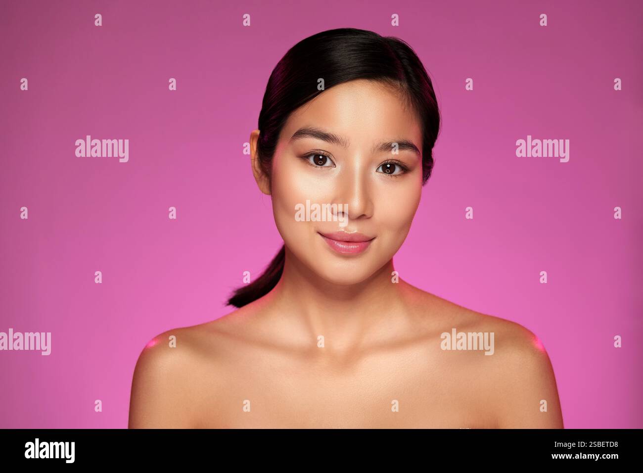 Model poses gracefully with soft expression against a vibrant pink ...