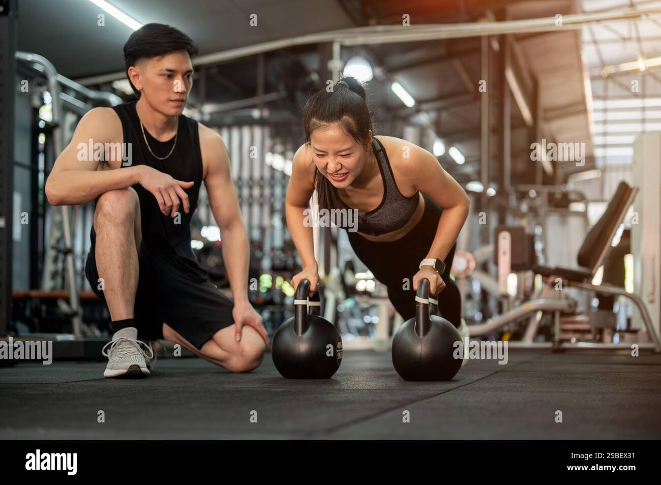 A determined Asian female client is being trained by a professional ...