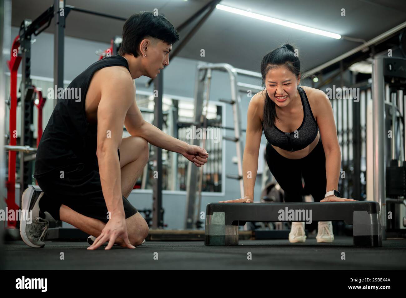 A focused and determined Asian woman is being carefully trained by a ...
