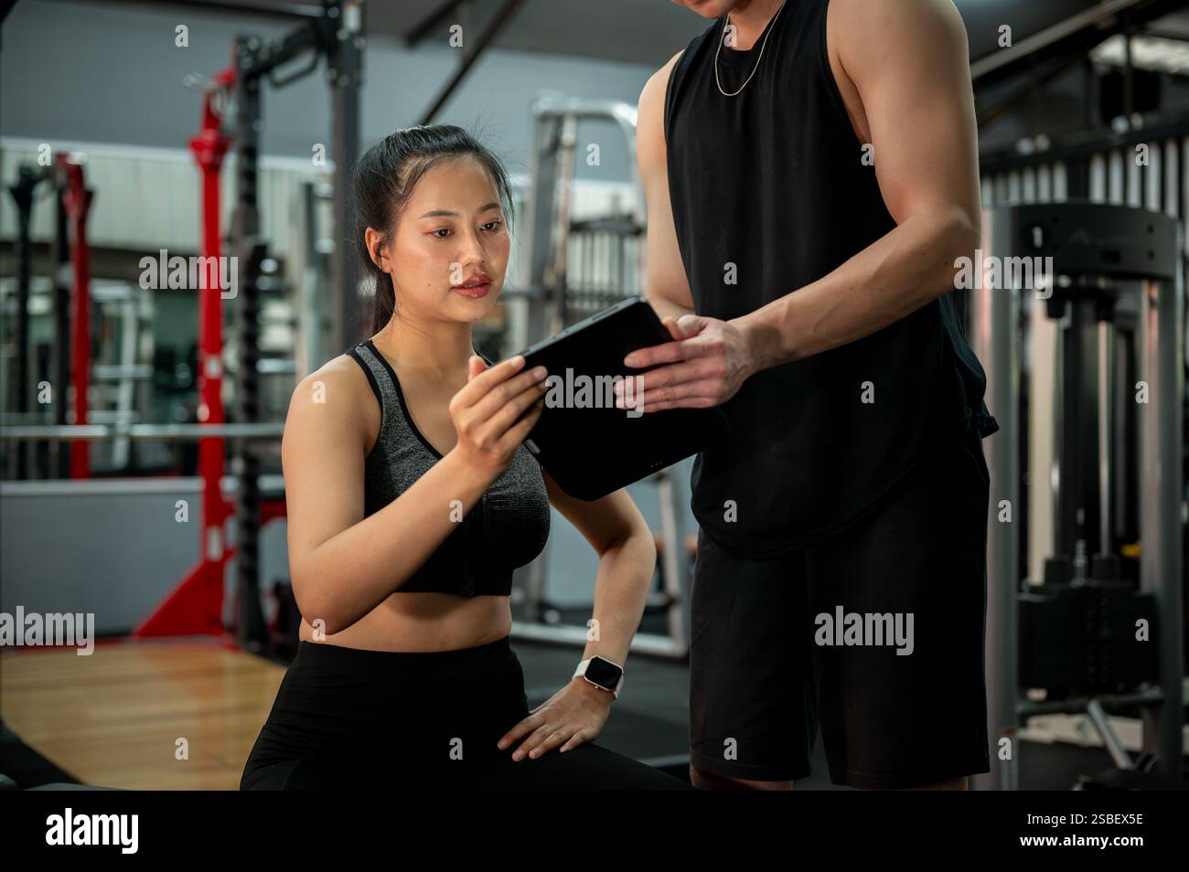 A beautiful and fit Asian female client in sportswear sits on a fitness ...