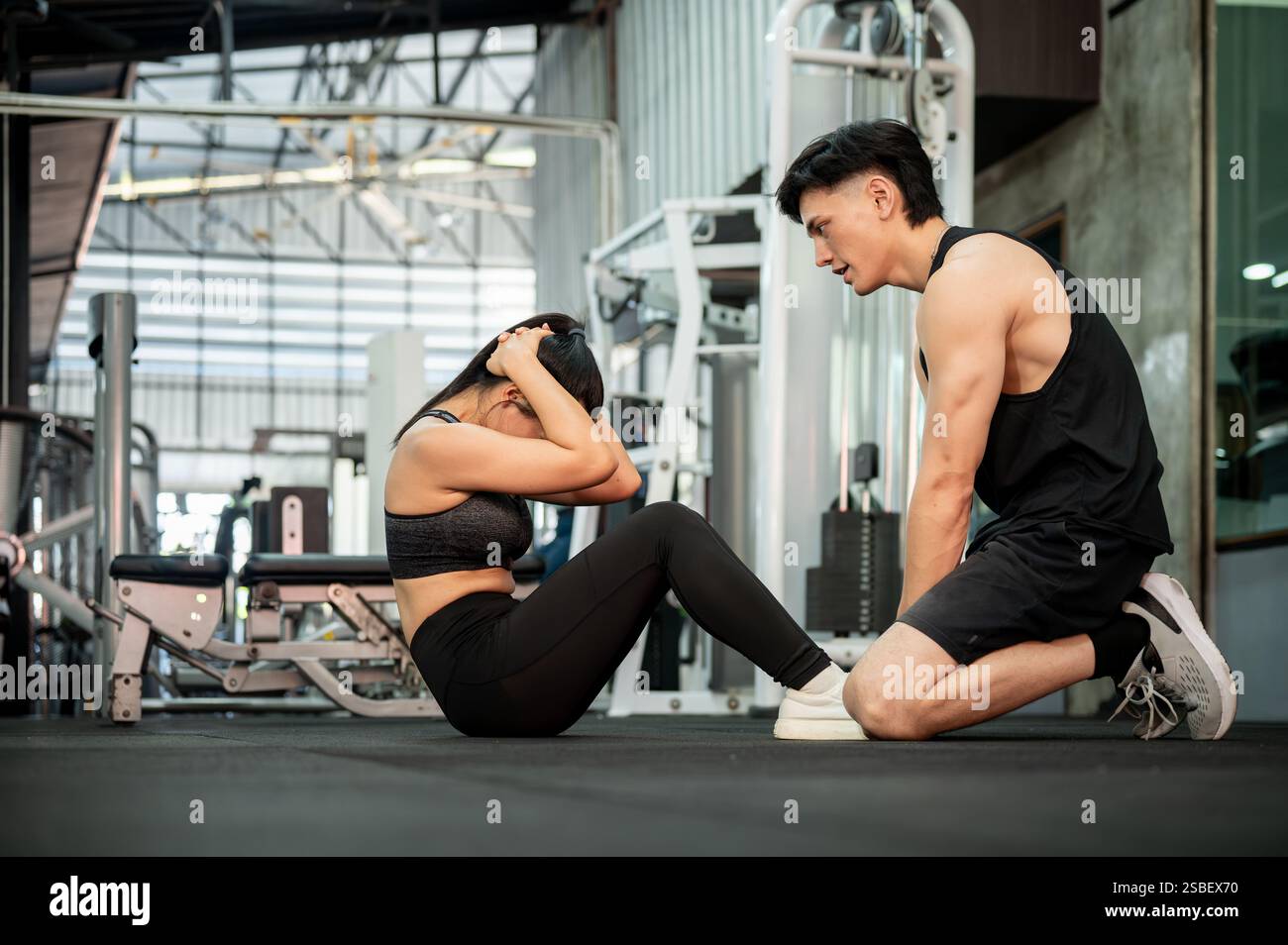 A professional and focused Asian male fitness trainer is instructing ...