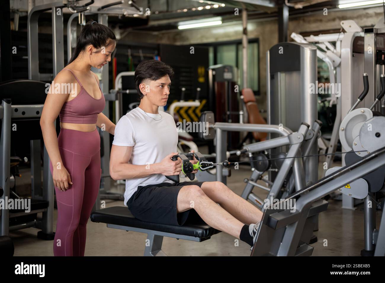 A supportive Asian female fitness trainer is training and instructing a ...
