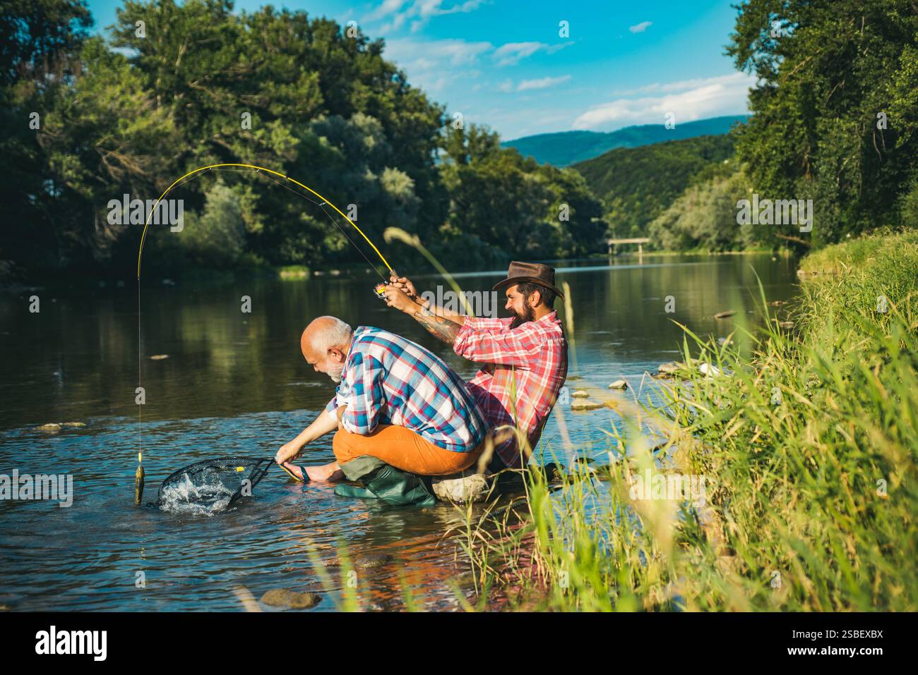 Portrait of cheerful senior man fishing. Grandfather and son fishermans ...