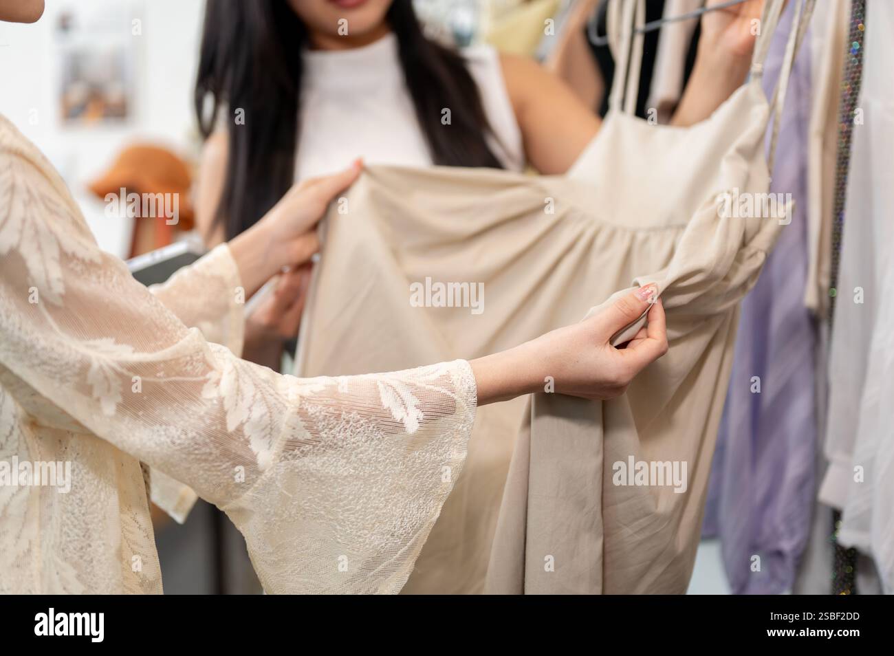 A close-up of a female customer gently touching the fabric of a dress ...