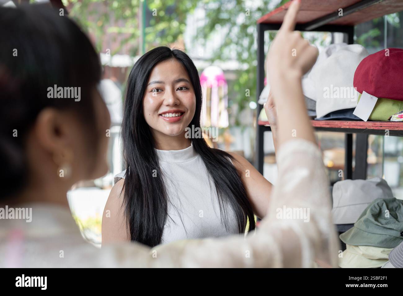 An Asian female customer is pointing at the item on the shelf she wants ...