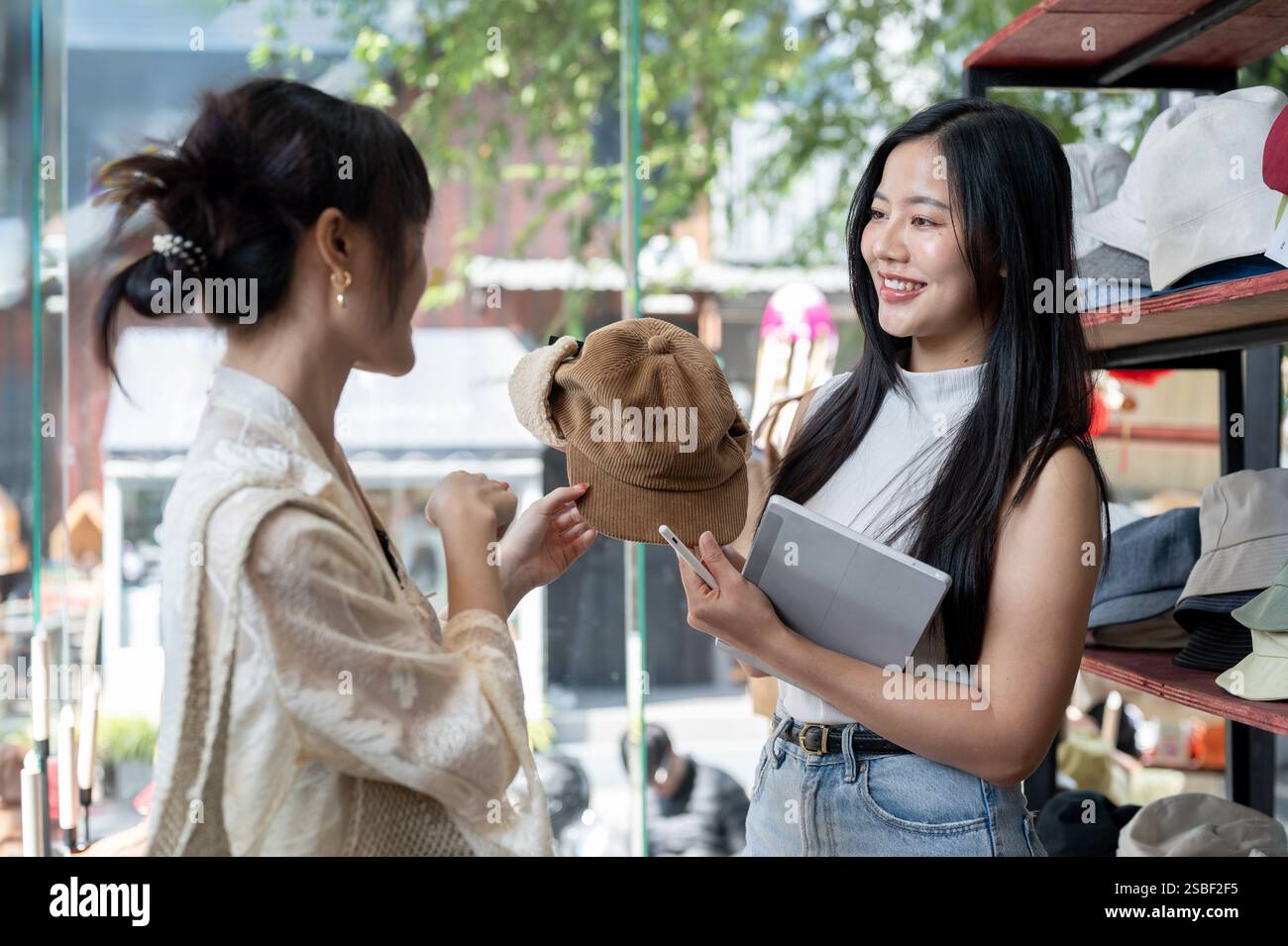 A cheerful and friendly Asian female shop employee is helping a ...