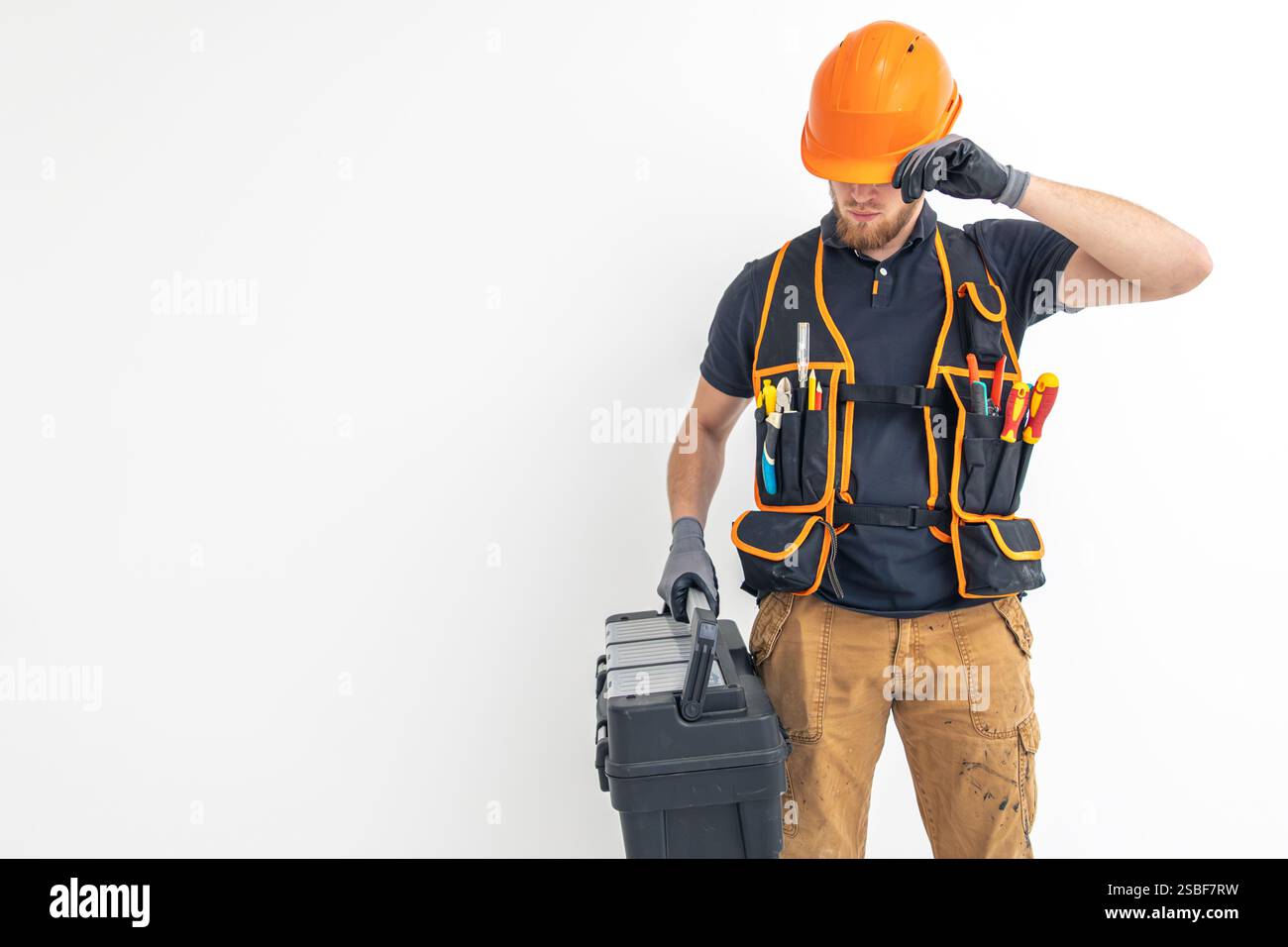 Male builder. Electrical engineer in overalls and helmet holds toolbox ...