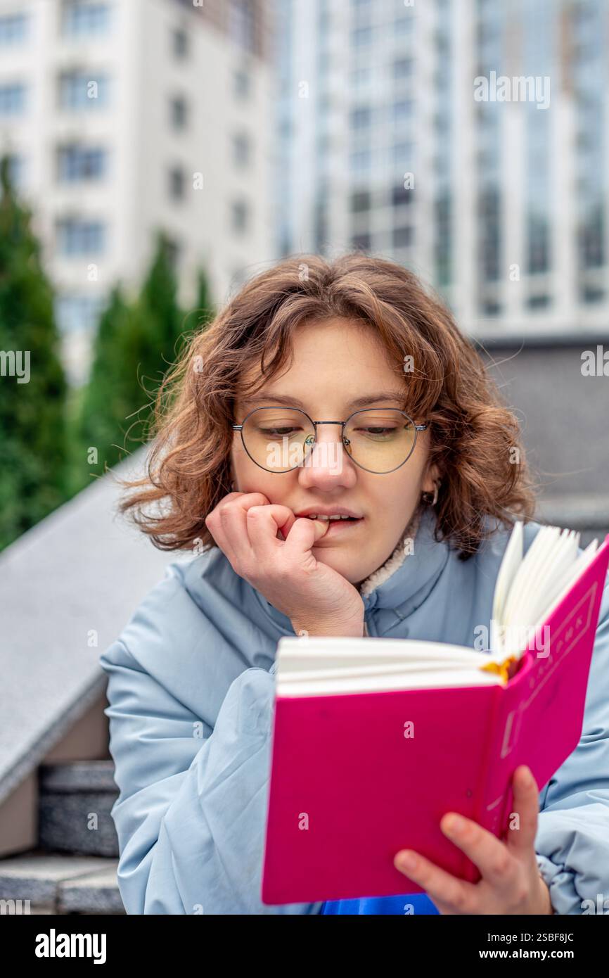 Girl reading a book on the street close-up. Teenage girl reading a book ...