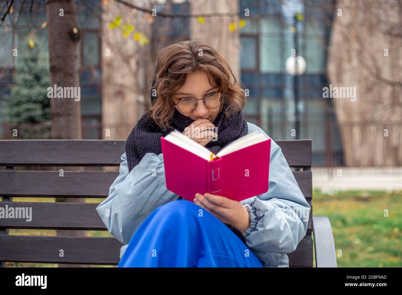 Girl reading a book on the street close-up. Teenage girl reading a book ...