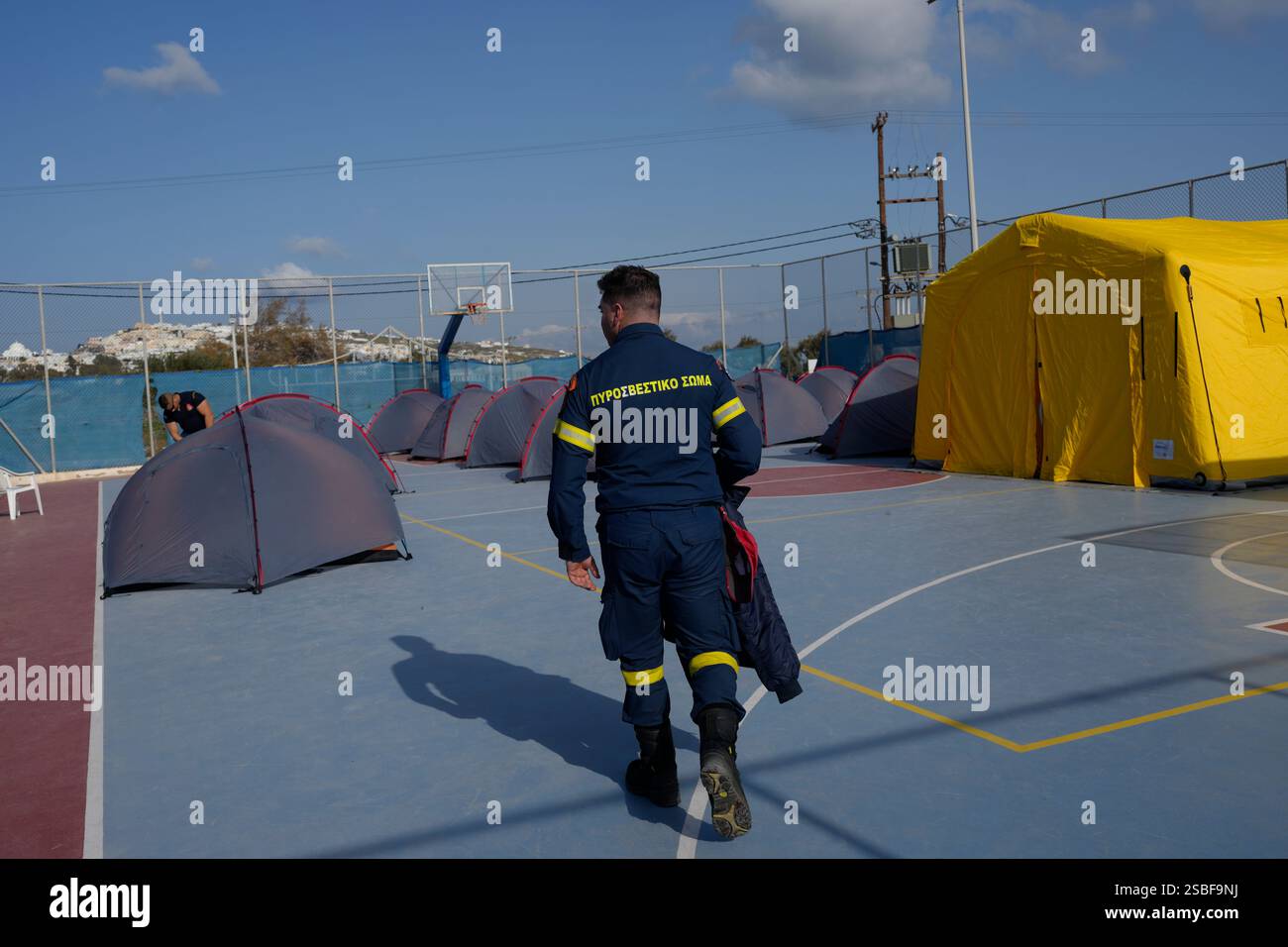 A firefighter walks next to tents set up at a basketball court to ...