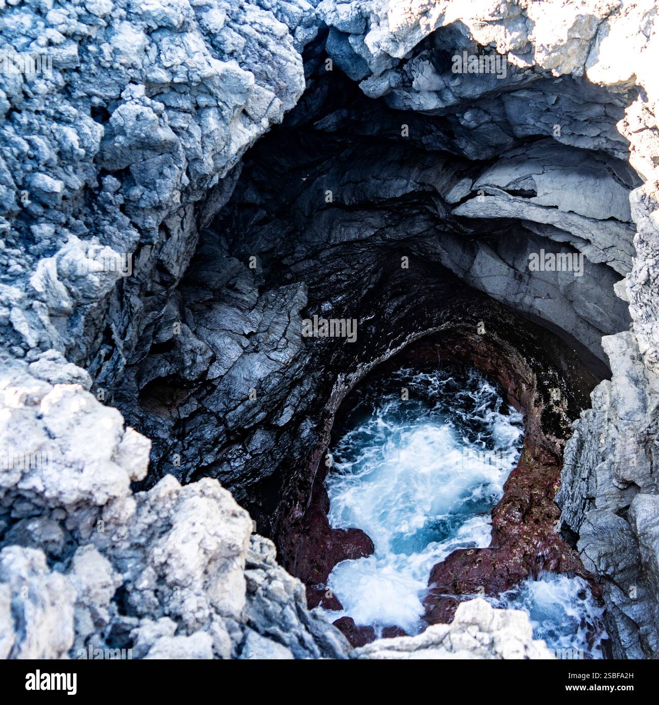 Aerial view of a rocky coastal area with a deep, circular opening ...