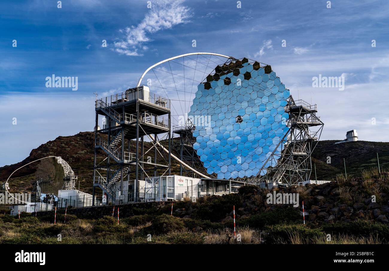 A large telescope with a hexagonal mirror array, set against a blue sky ...
