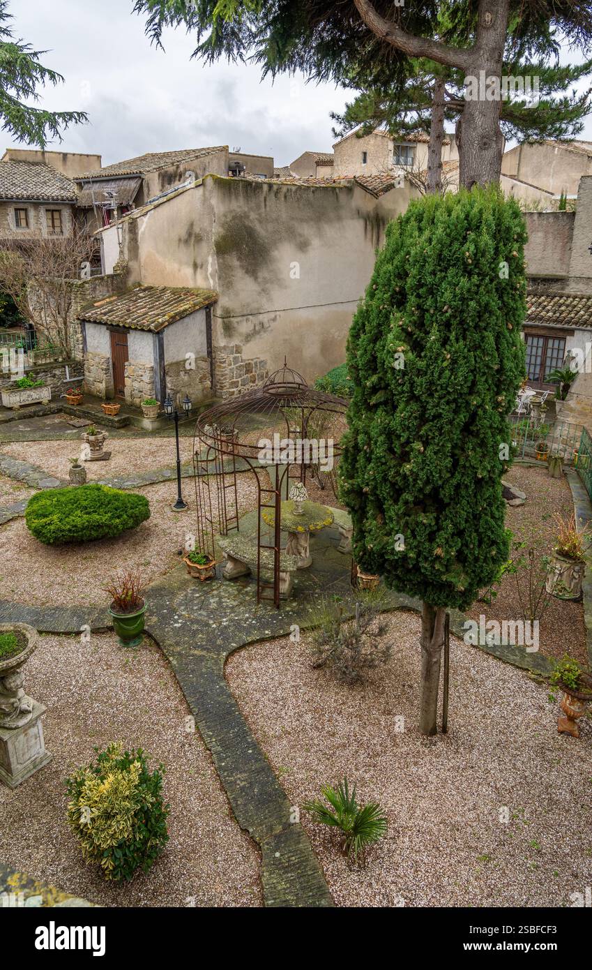 Rustic courtyard with stone table and greenery surrounded by old ...
