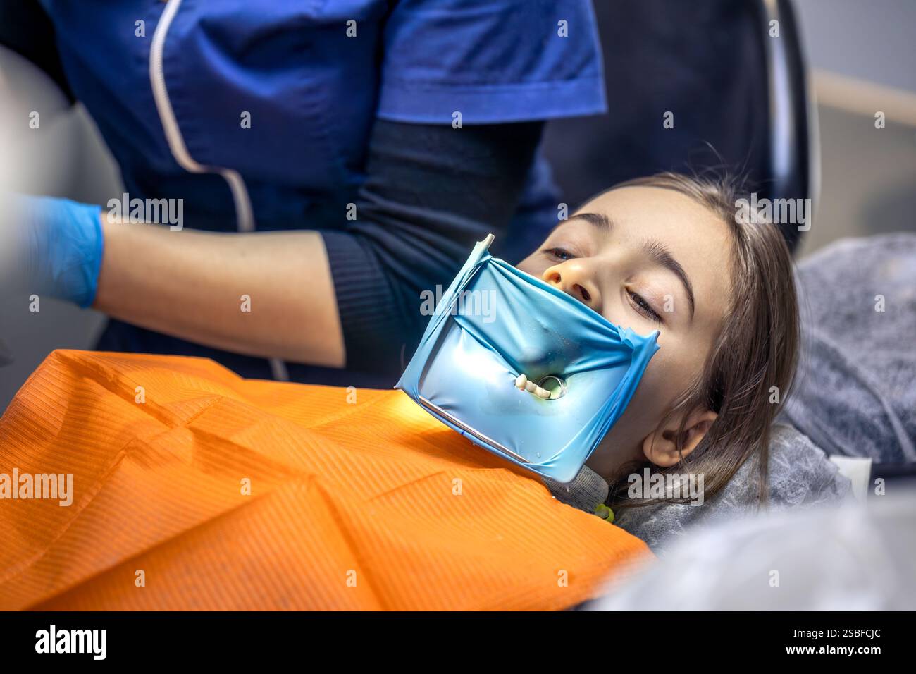 The dentist treats the child's tooth using a rubber dam. Close-up of ...