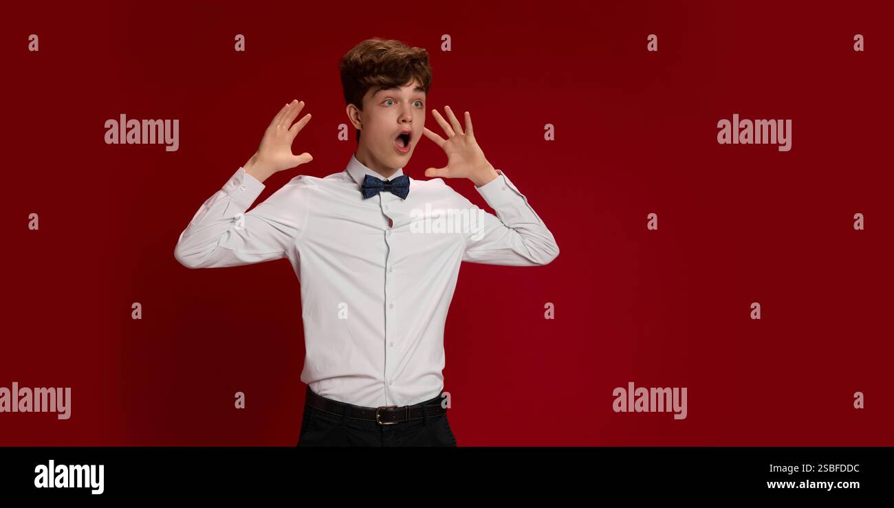 Portrait of young man, student in white shirt and bow tie emotionally ...