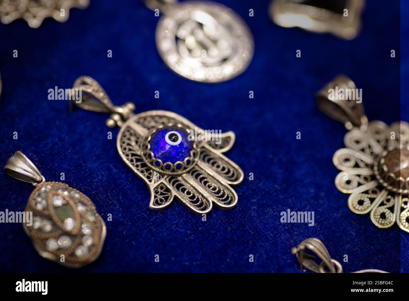 A silver Hamsa pendant featuring a blue evil eye for protection and ...