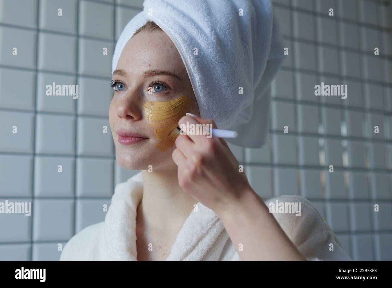 A woman applies a facial mask in a serene spa, enhancing her skincare ...
