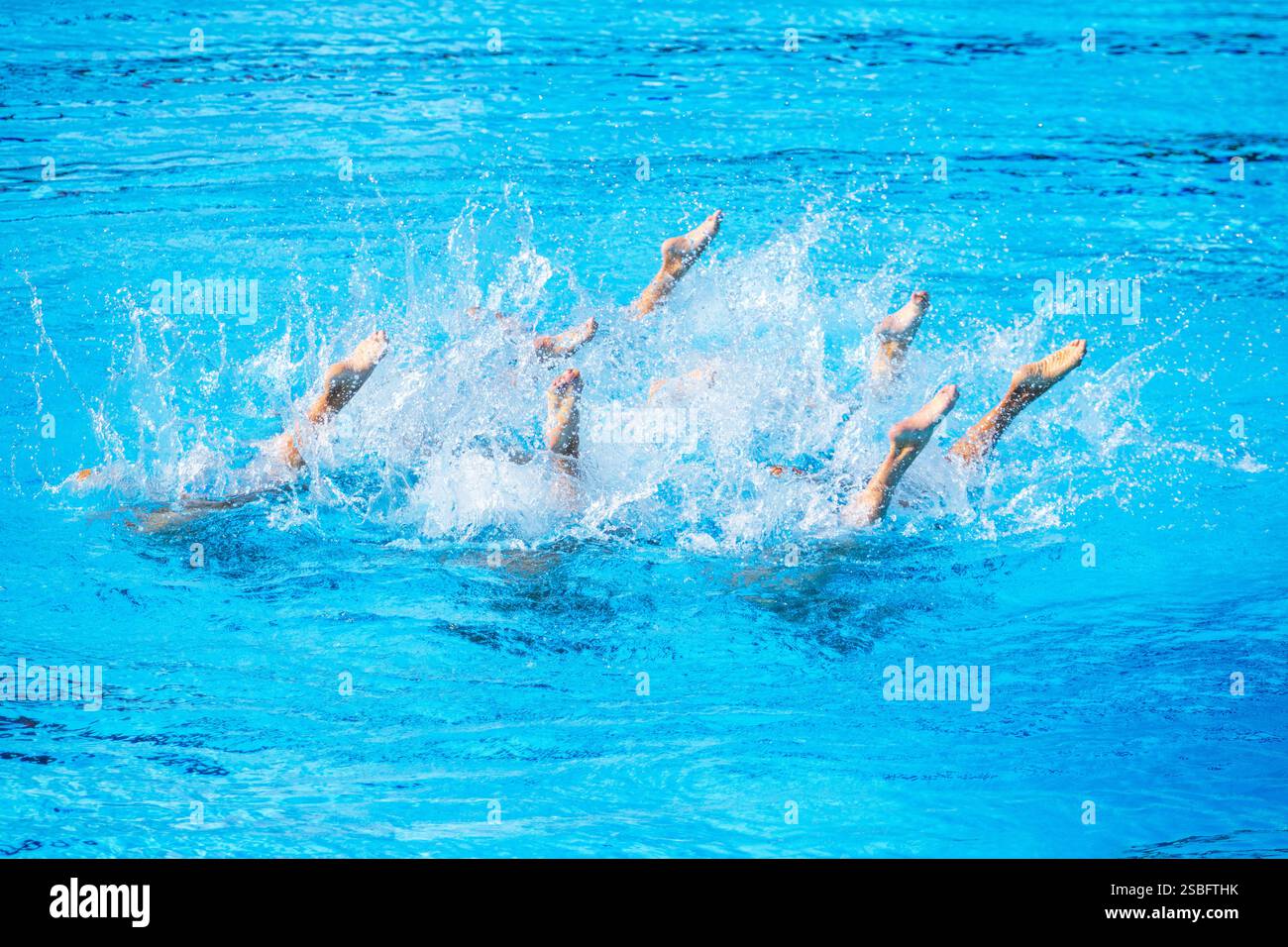 Artistic swimmers team performing synchronized legs movement in ...