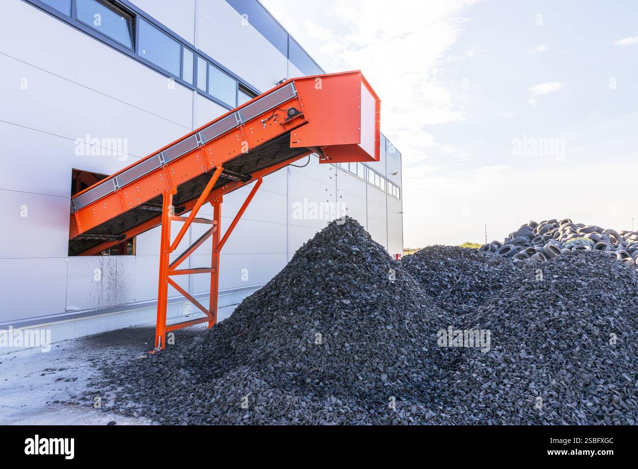 Tire recycling. Industrial conveyor belt transporting shredded rubber from a recycling facility ...