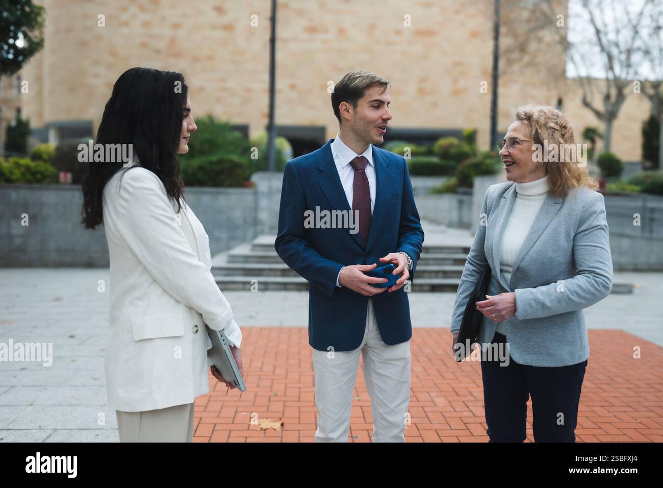 Businesspeople talking outside office building during work break Stock ...