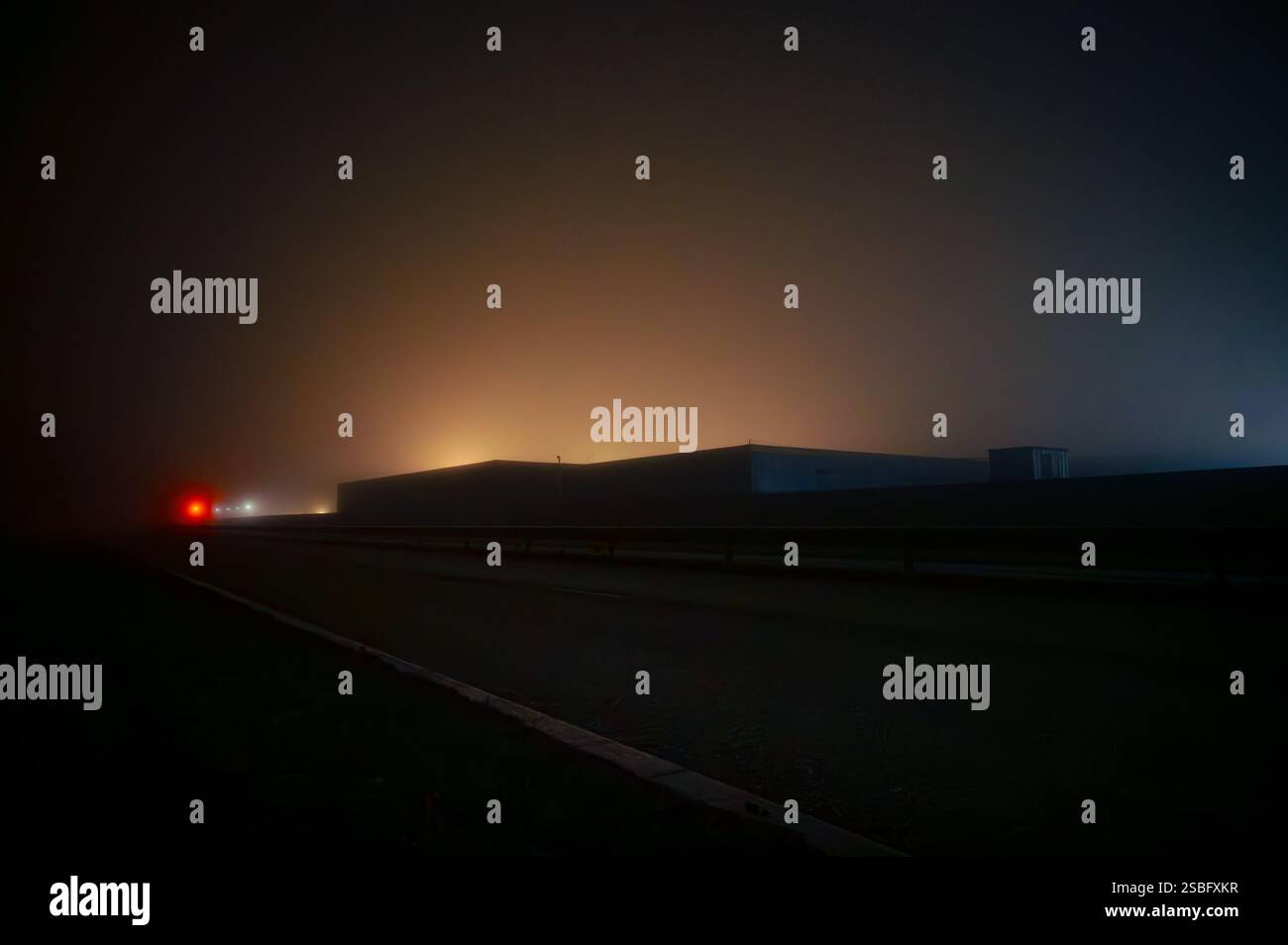 A liminal picture of a warehouse or factory in the mist next to an ...