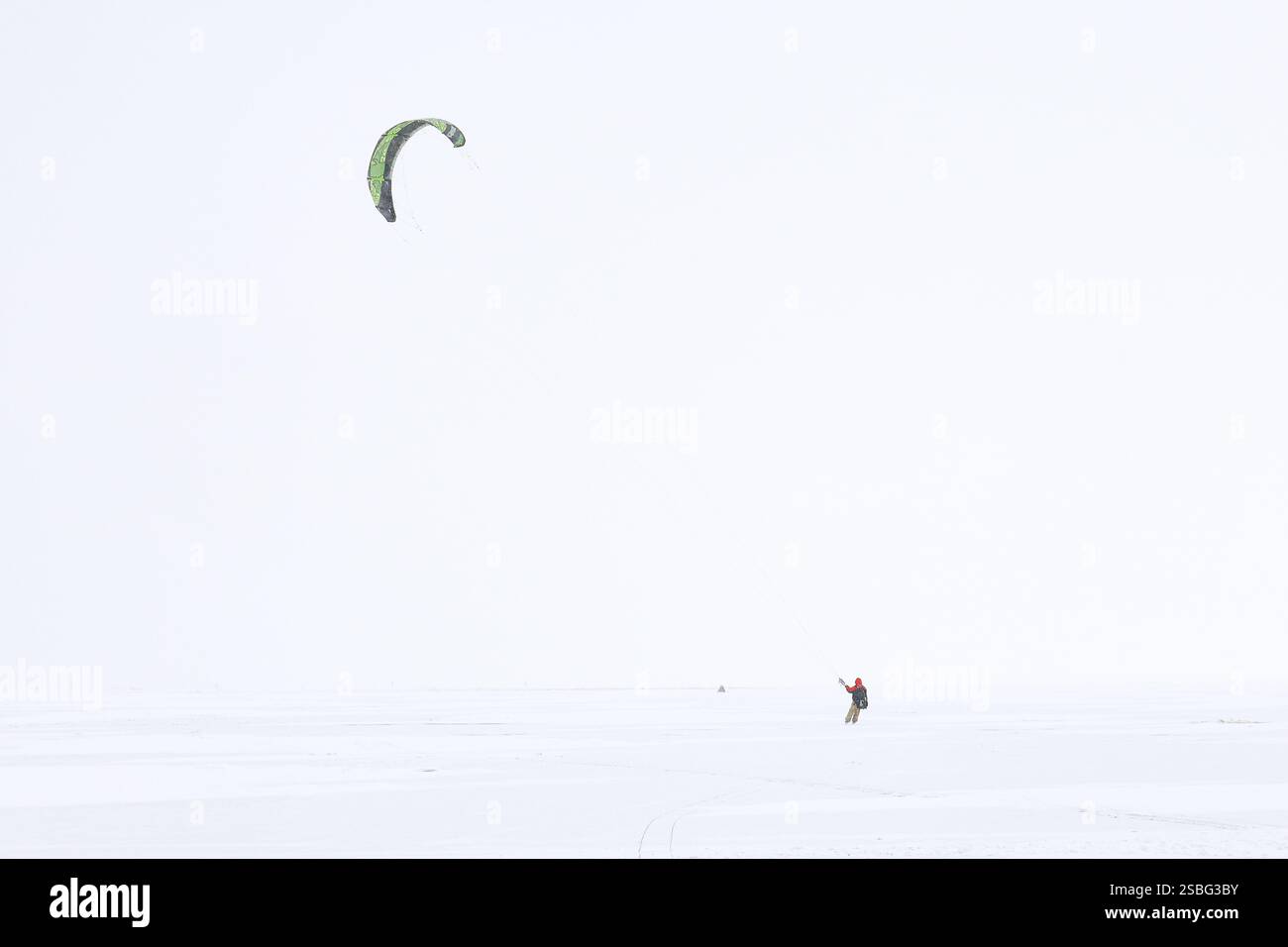 A male snowkiter rides a snowboard on the ice of the Gulf of Finland ...