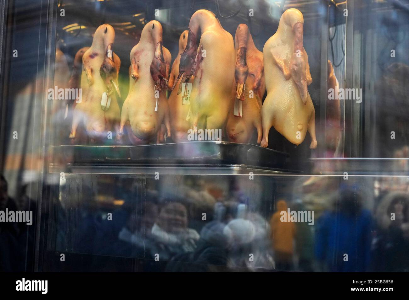 People are reflected on the window of a Peking Duck dish display at a ...