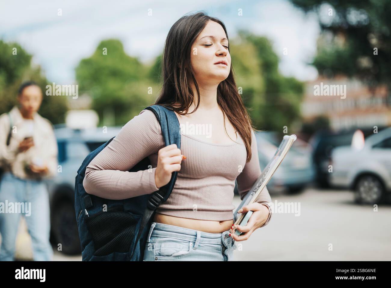 Confident student walking on campus with books and backpack Stock Photo ...