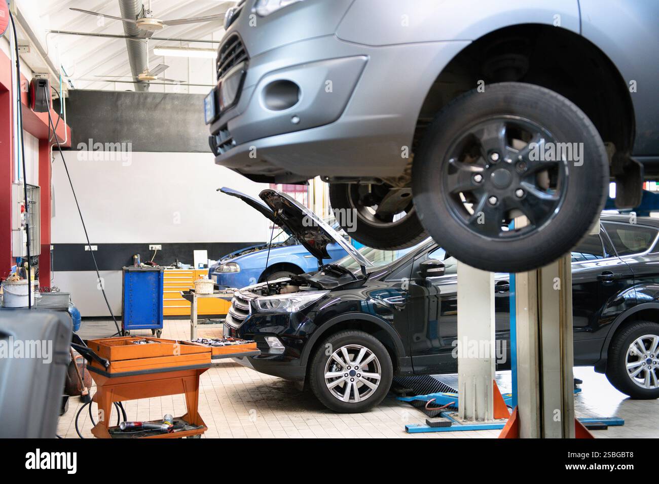 Cars being serviced in a professional auto repair shop, showcasing the automotive maintenance ...