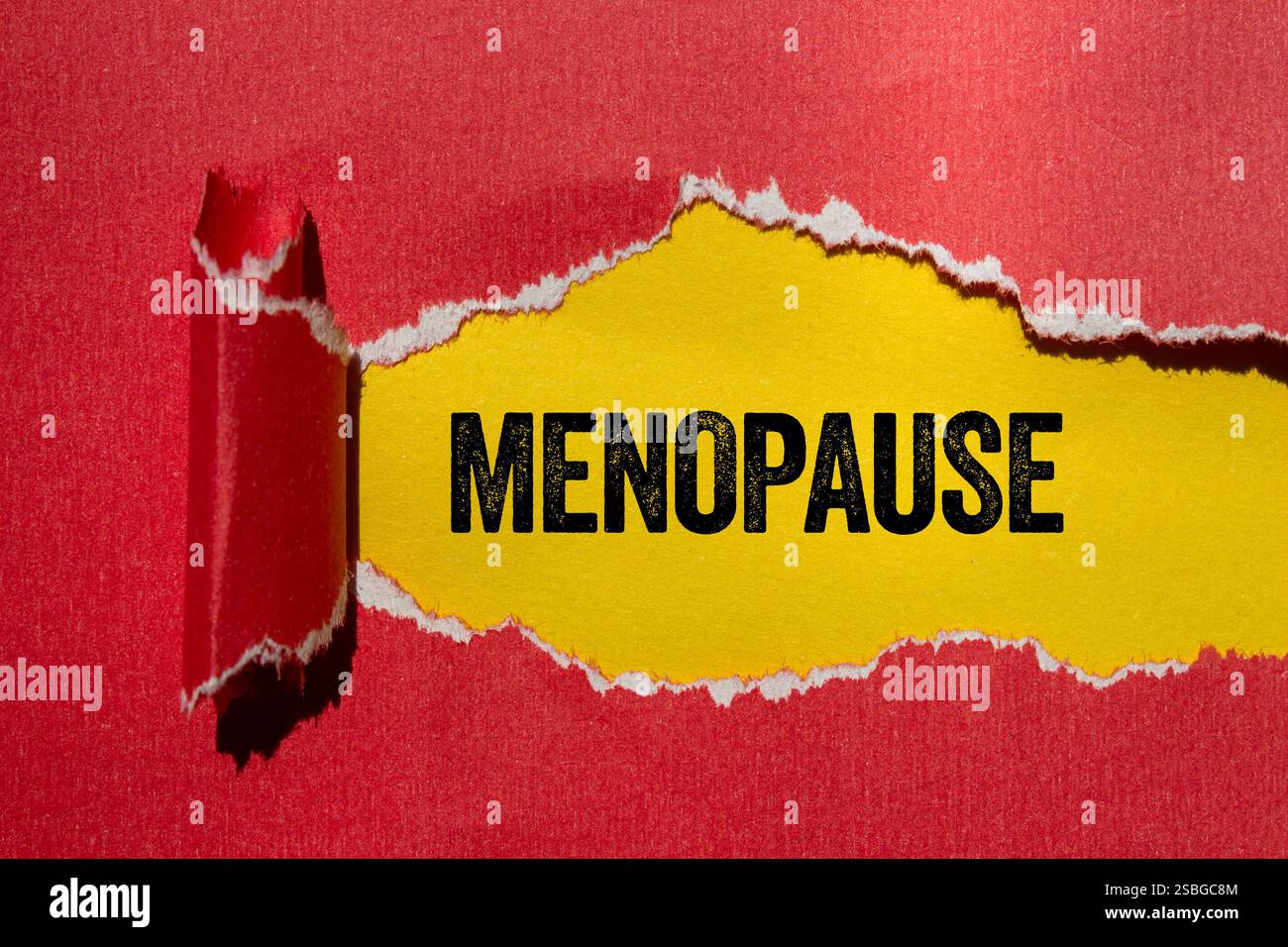 Menopause message written on ripped torn red paper on yellow background ...