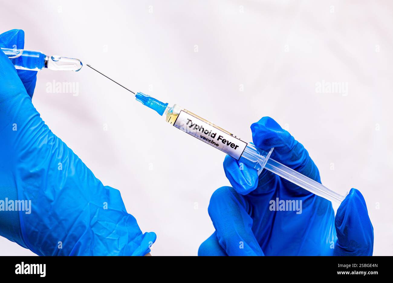 Close-up of vial with blank label in hand with glove. Fluid being ...