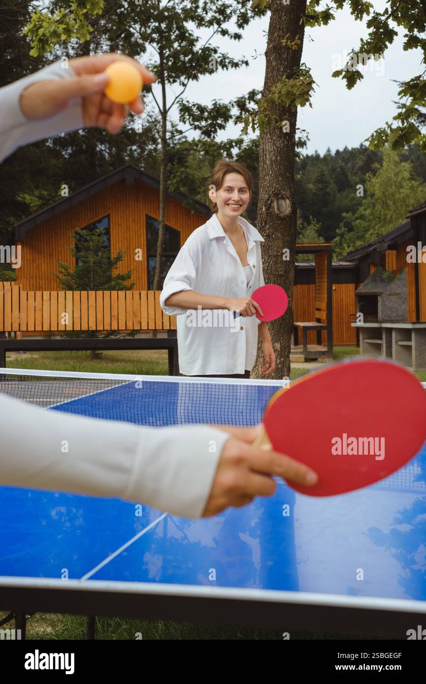 Women enjoy a active game of ping pong in modern outdoor resort ...