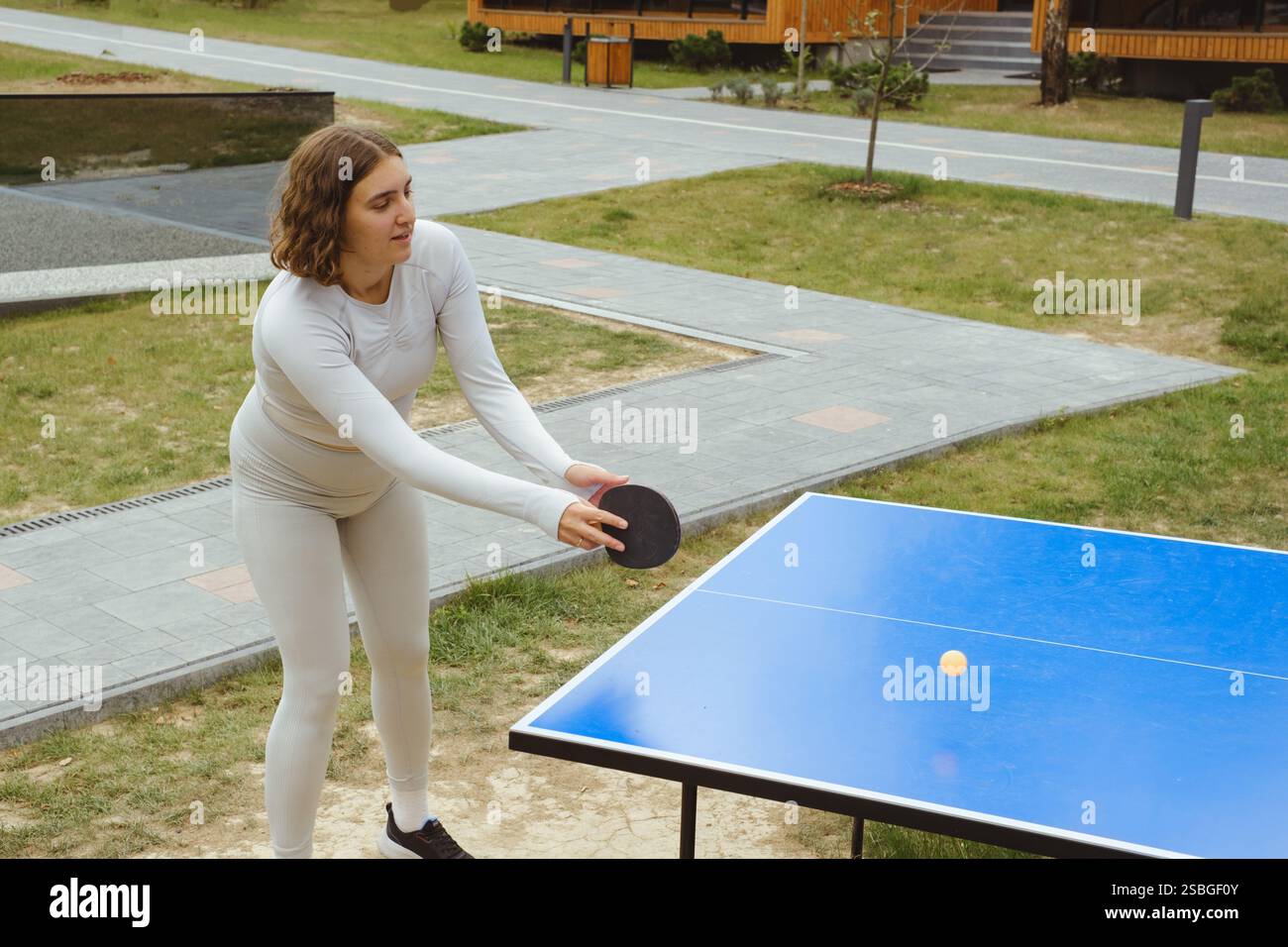 Women enjoy a active game of ping pong in modern outdoor resort ...