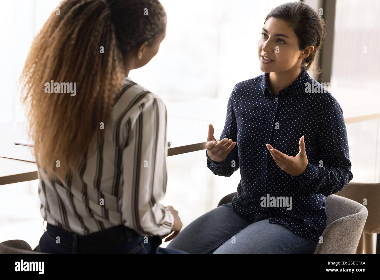 Two women engaged in conversation, discussing joint work-related topics ...