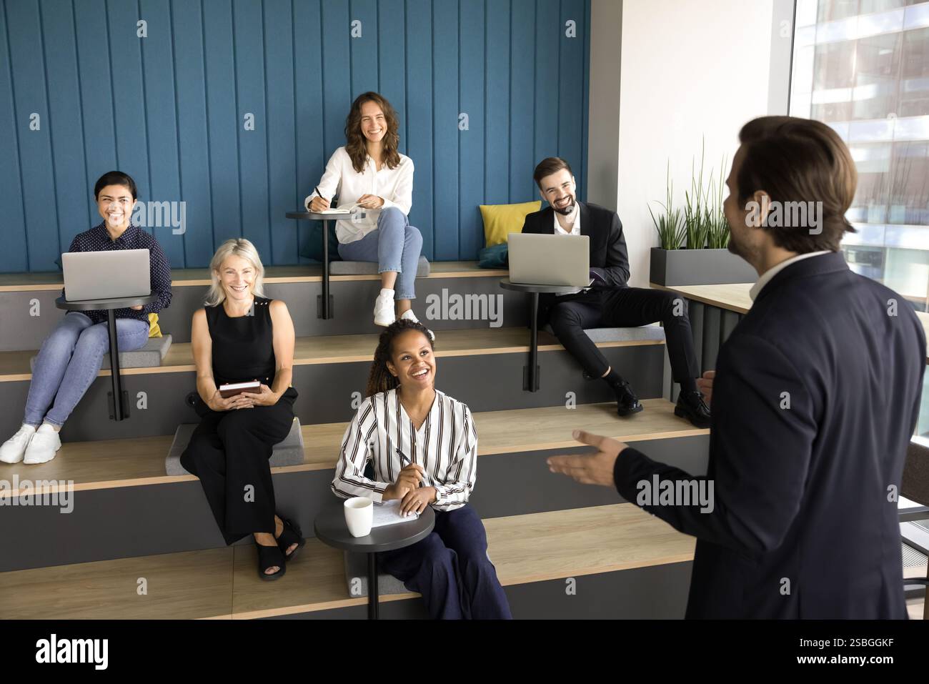 Male presenter makes speech standing in front of team Stock Photo - Alamy