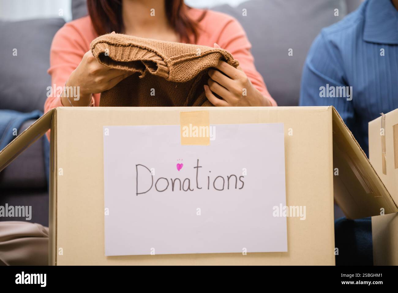 group of friend sorting and packing clothes into a donation box ...
