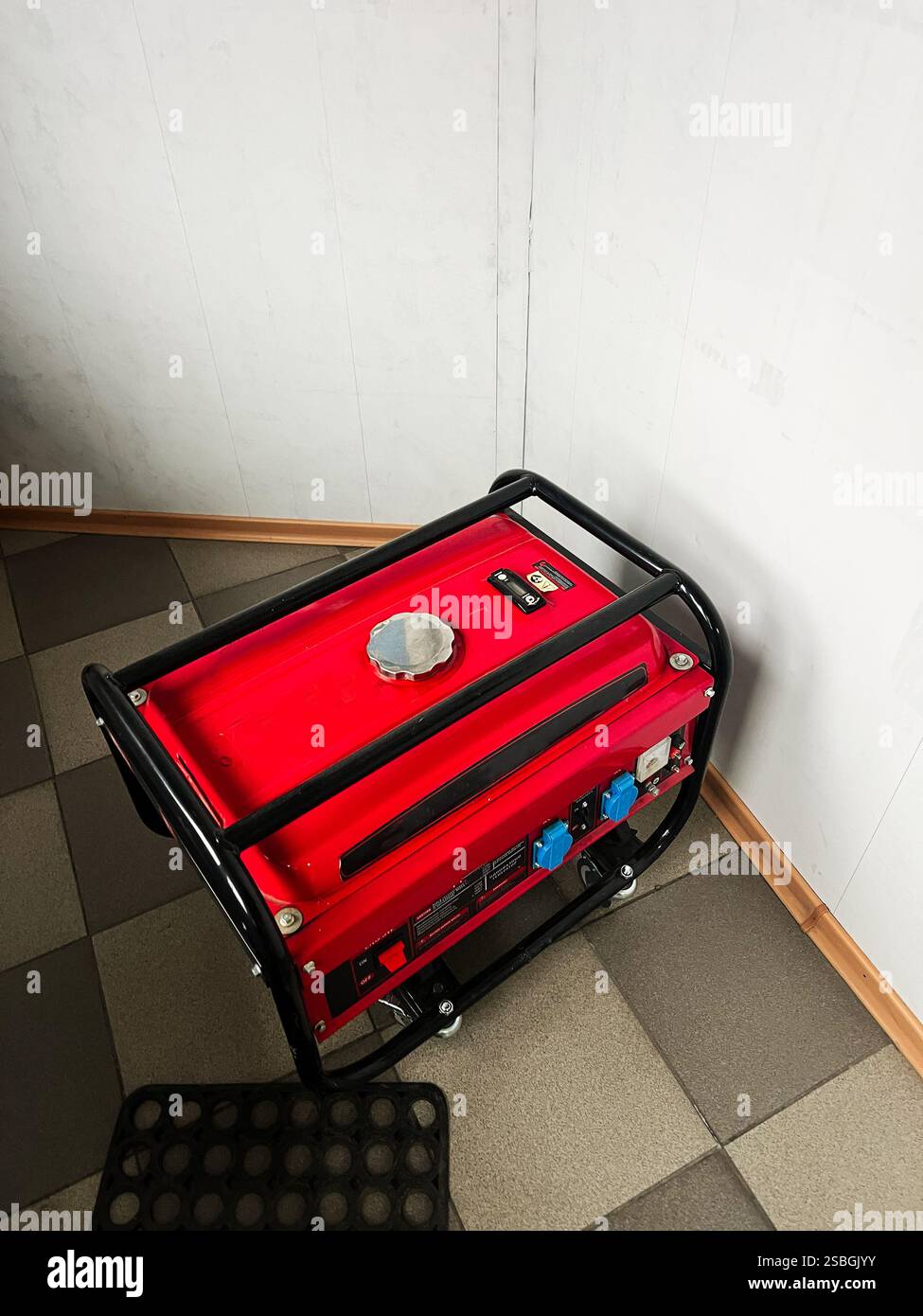 A red portable generator standing indoors on a tiled floor, equipped ...