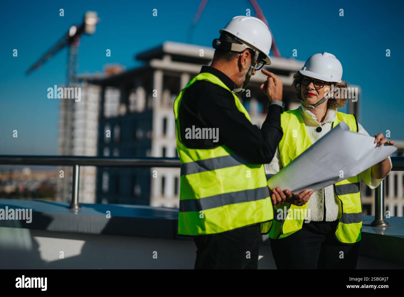 Two architects on construction site discussing blueprints Stock Photo ...
