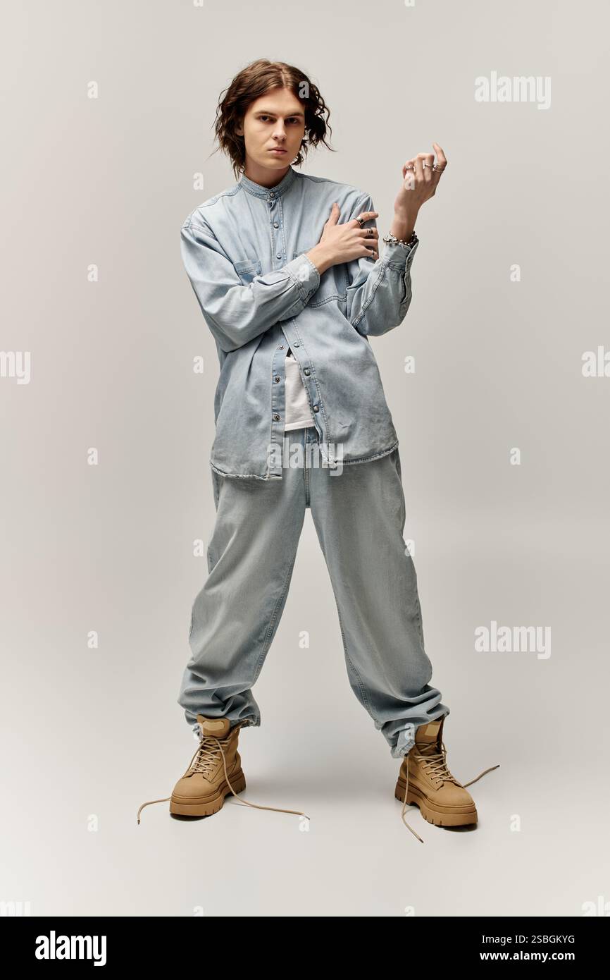A handsome young man showcases a trendy denim outfit while striking a ...