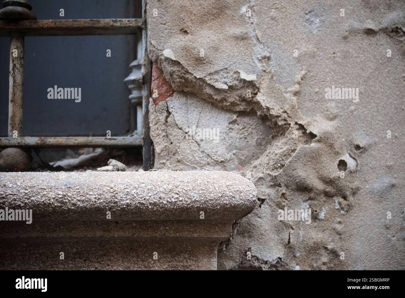 A weathered stone wall shows significant deterioration and damage, with ...