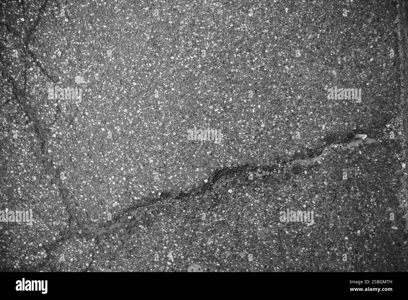 Close-up view of asphalt pavement showing a crack running diagonally ...