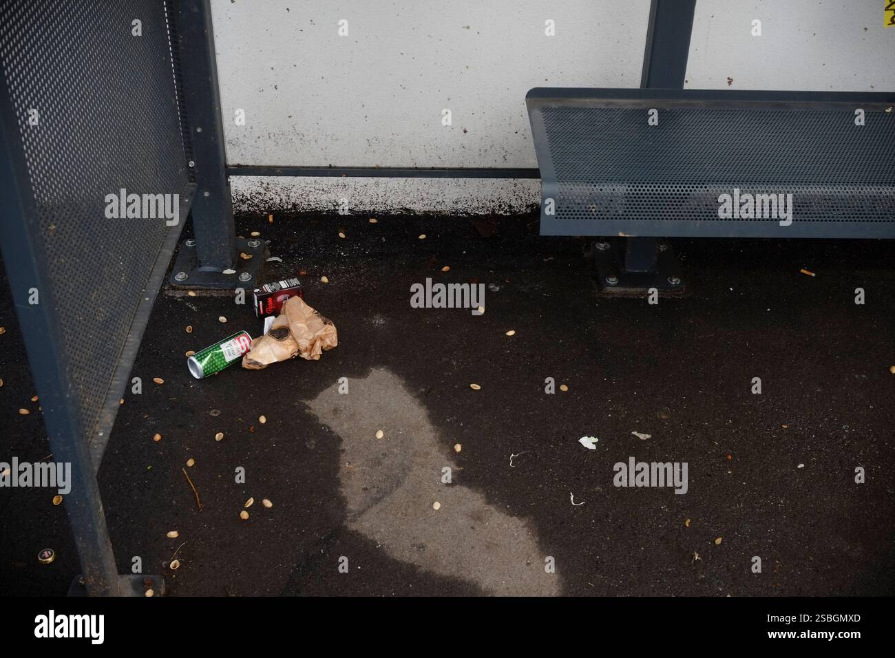 Litter scattered on the ground near a bus shelter. Discarded food ...