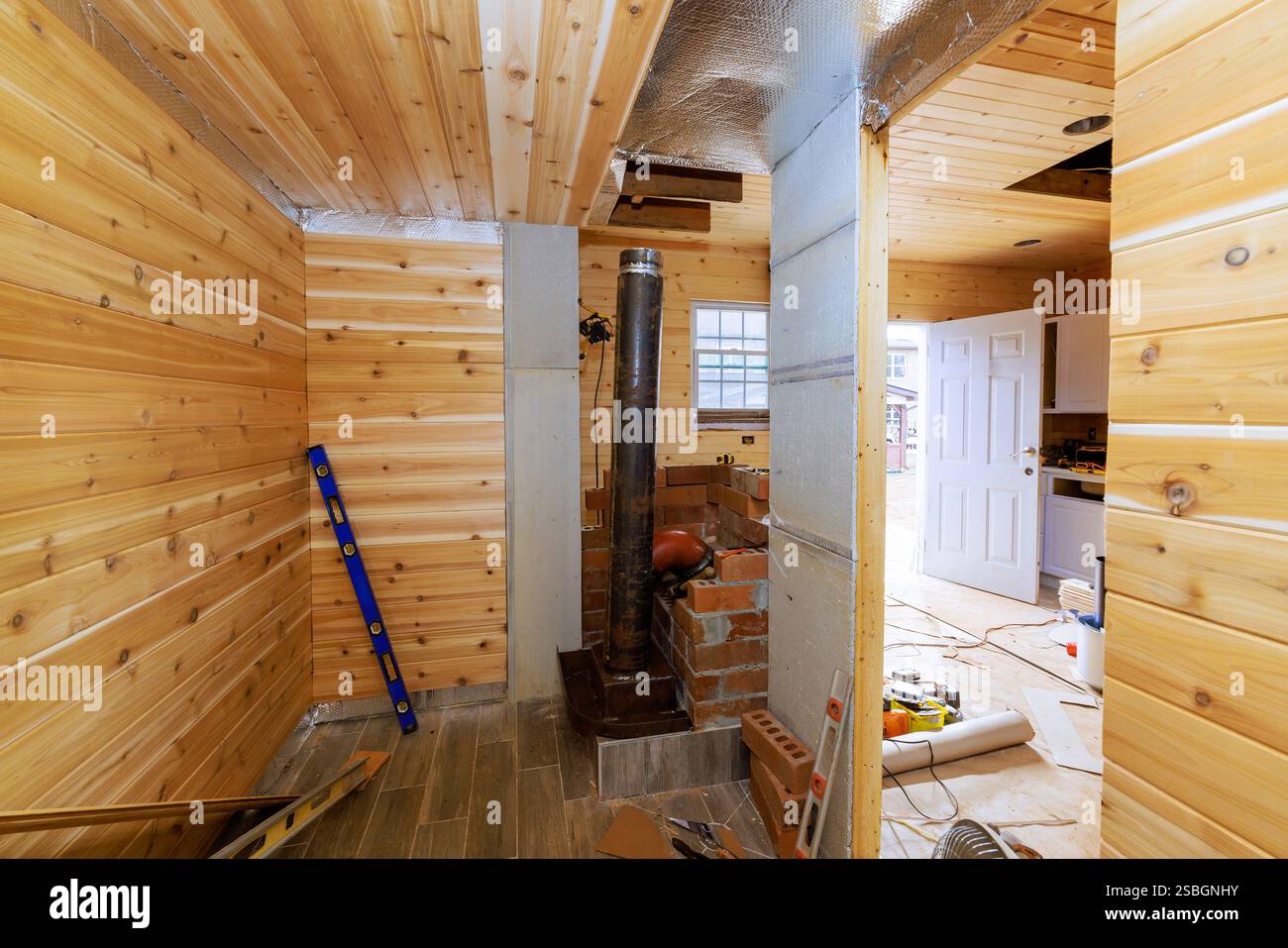 Interior renovation ongoing in sauna cabin with wooden walls heating stove, construction tools ...