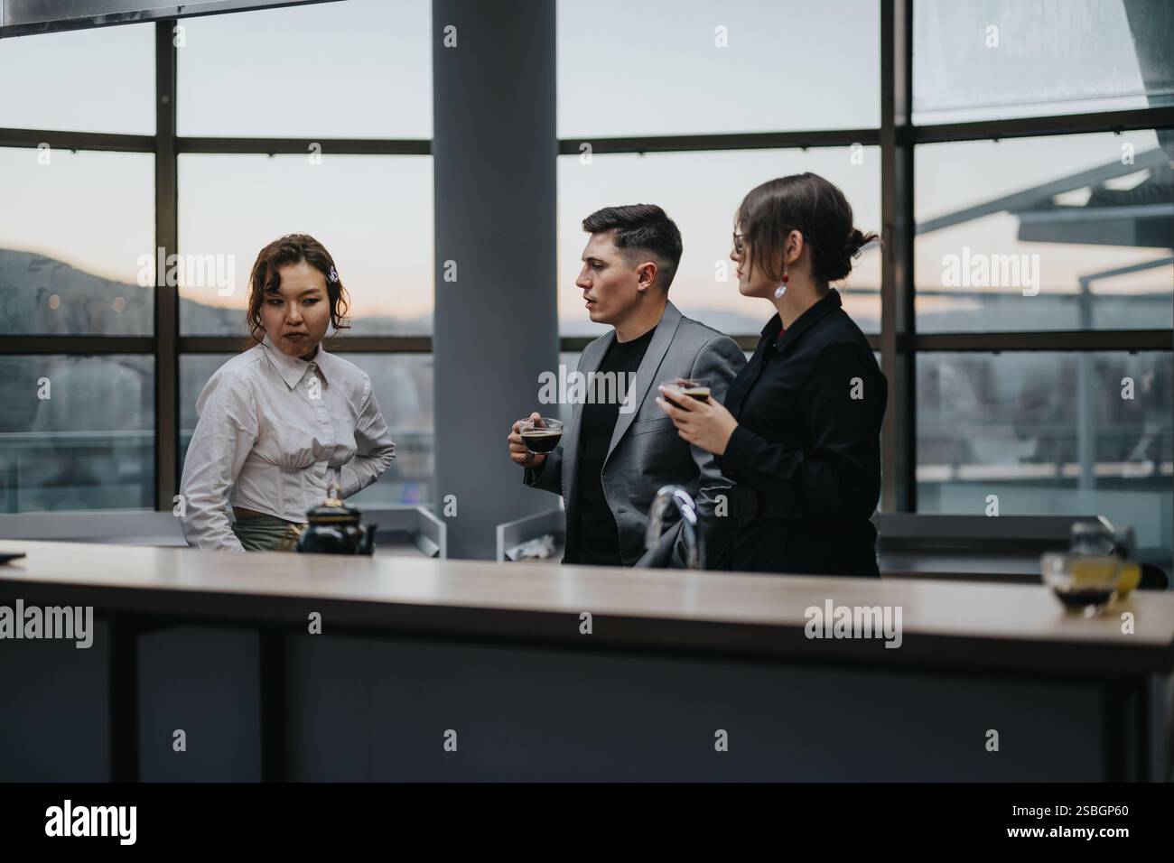 Three business professionals engage in conversation during a coffee ...
