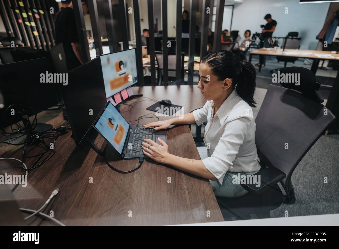 Woman working at a desk in a modern collaborative office environment ...