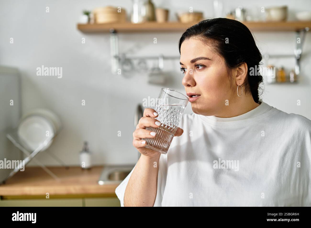 A lovely young plus sized woman relaxes while sipping water in a ...